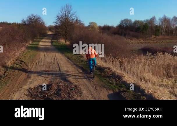 Man in orange jacket cycling outdoors Stock Video Footage - Alamy
