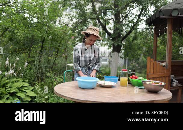 Young woman in a straw hat preparing a healthy meal with fresh ...