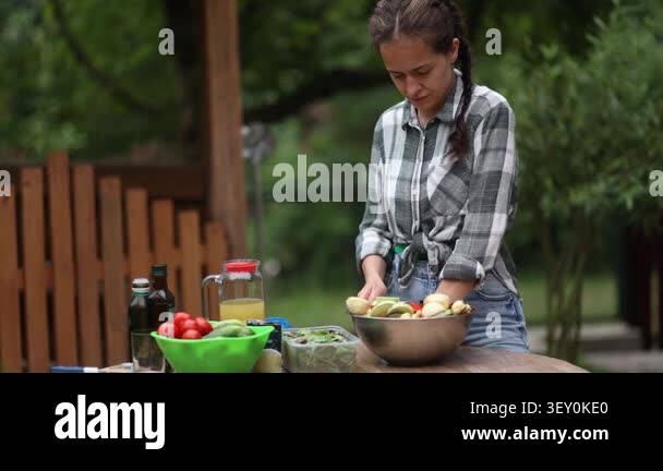 Beautiful young woman mixing a fresh vegetable salad in a bowl. She is ...