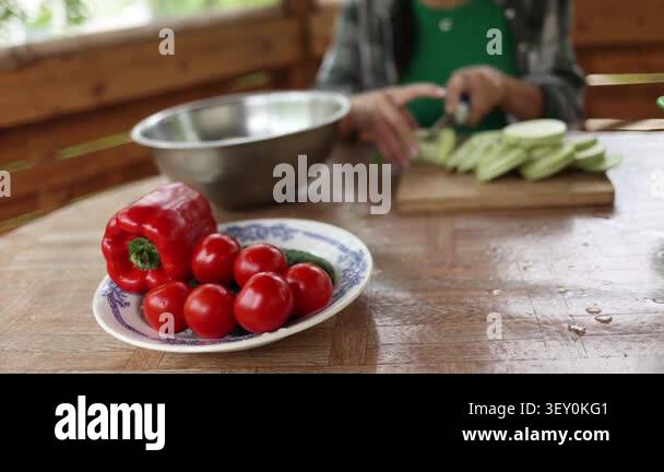Womans hands using a knife to slice fresh zucchini on a wooden cutting ...