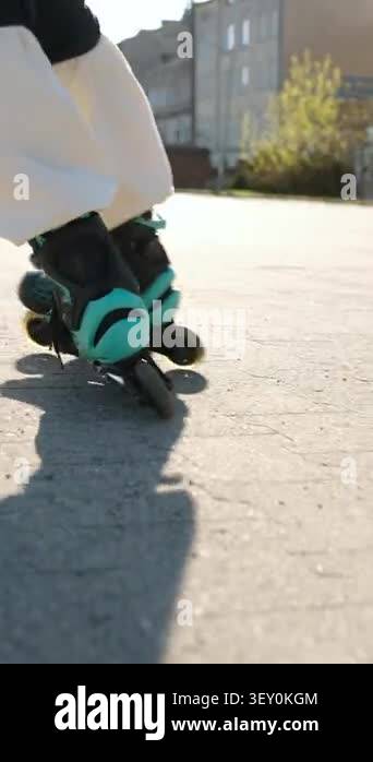 Girl wears turquoise roller skates, gliding on a paved urban path ...