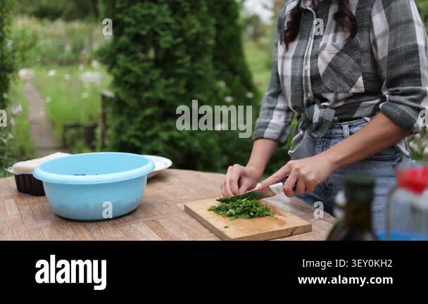 Womans hands finely chopping fresh green parsley on a wooden board ...