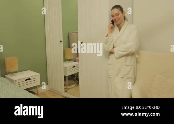 Beautiful smiling woman wearing a white bathrobe while having a ...