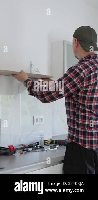 Man Aligning Shelf On Kitchen Wall For Fitting In Workspace Preparing ...