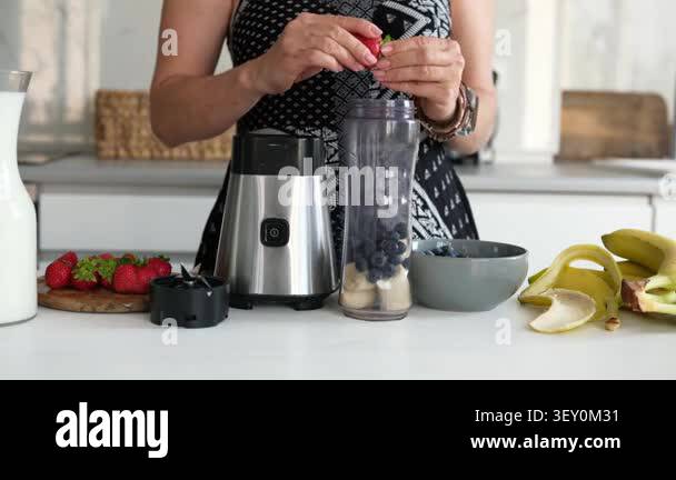 Woman Making A Cocktail With Banana Strawberries And Blueberries Stock ...