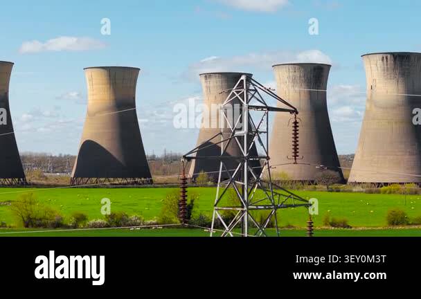 Transmission pylon standing in farmland with nuclear cooling towers in ...