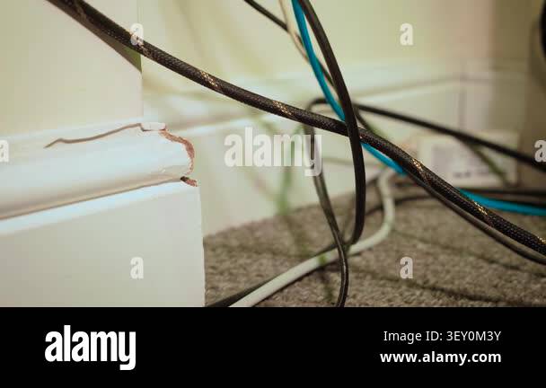 Loose computer cables scattered behind desk and across carpet floor ...