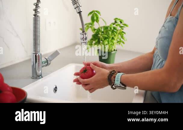 Young Woman Rinses Fresh Tomatoes In The Kitchen For A Healthy ...