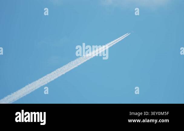 Airliner flying high leaving long white contrail across blue sky ...