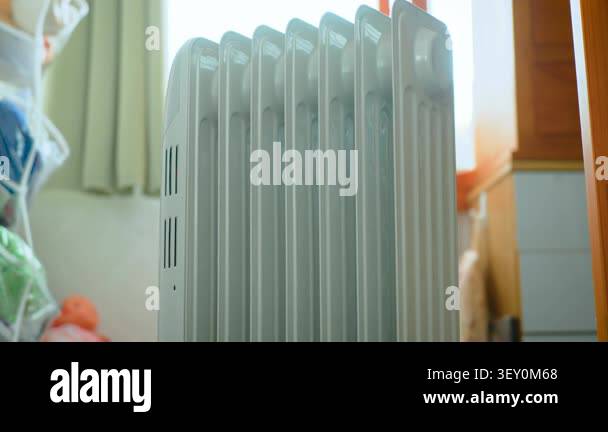 White oil radiator standing on carpet in modern home interior. Electric ...