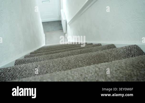 Narrow carpeted stairs descending toward hallway door in private house ...