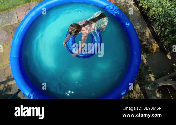 Child jumping on floating swim ring inside home inflatable pool during ...
