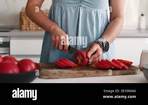 Young Woman Slices Fresh Tomatoes On A Cutting Board In The Kitchen For ...