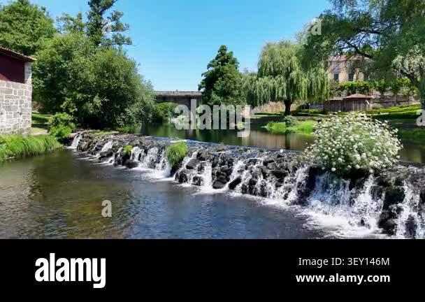 Peaceful view of the Arnoia river with a small weir and an old stone ...