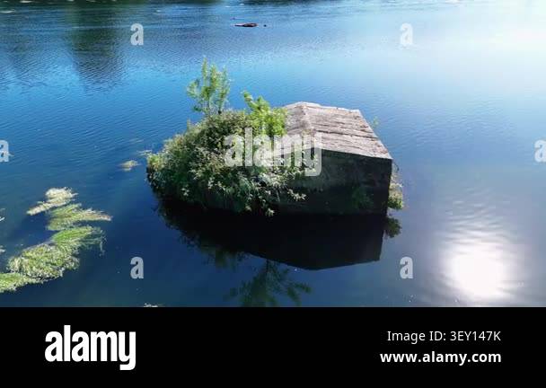 Remains of an old stone building, possibly a bridge pier, emerging from ...
