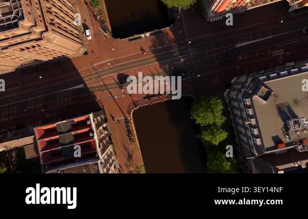 Drone orbits above an Amsterdam canal intersection featuring a tram ...