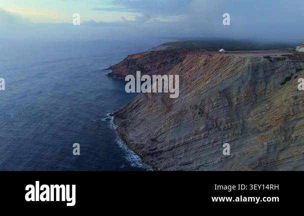 Drone view of steep layered rock cliffs rising above the ocean with ...