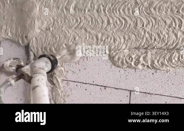 A worker applies gypsum plaster to interior walls using a plastering ...