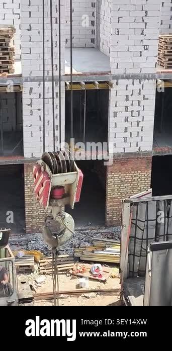 Construction crane lifting a large metal cargo hook suspended on steel ...