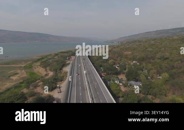 Aerial view of highway running along river and green hills ...
