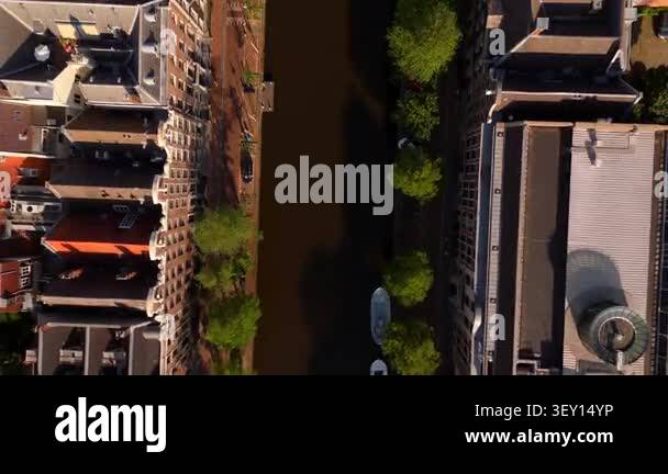Drone looks straight down at a narrow canal running between a modern ...