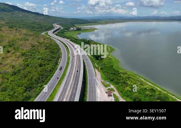 Aerial view of highway running along river and green hills ...