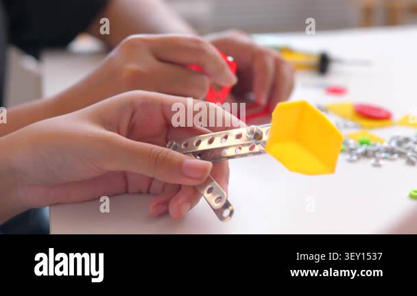 Close up of child hands assembling 3D printed robot model on table ...