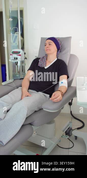 Woman receiving intravenous cancer treatment while seated in medical ...