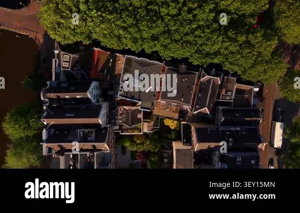 Top down drone view captures a sunlit Amsterdam canal with a bridge ...