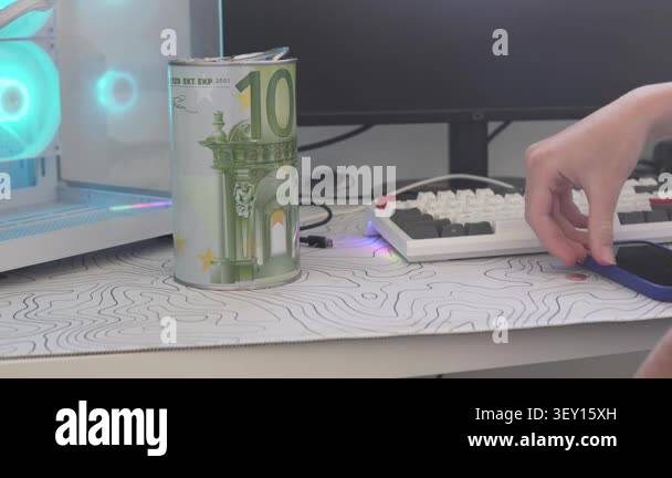 Close-up of a hand putting coins into a savings bank with printed money ...