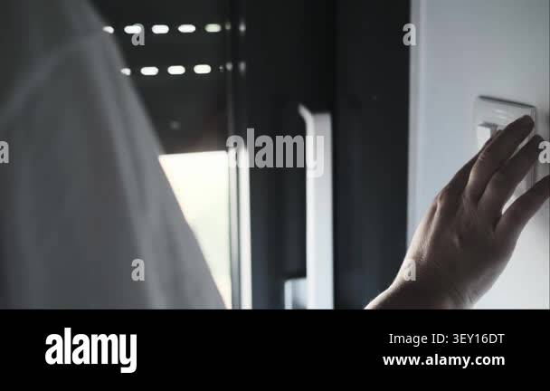 Close up view of womans hand turning on electric blinds in smart home ...
