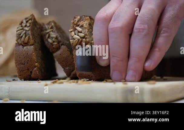 Close up footage of a person slicing dark seeded bread with a bread ...