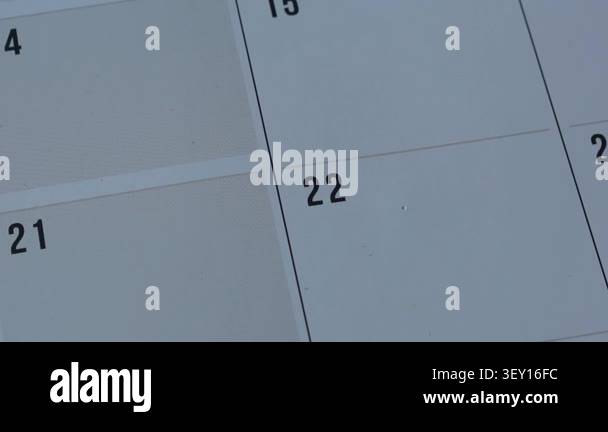 Female hand using a red marker to circle a date on a desk calendar or ...