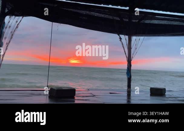A stunning sunset view over the ocean from a shaded beachside structure ...