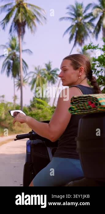 Vertical video. Woman Sitting on Scooter Showing Hand Gesture Toward ...