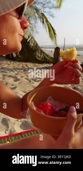Vertical video. Close Up Side View Of Woman Eating Mini Pineapple Slice ...