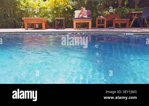 Low Angle View Across Clear Swimming Pool Water Toward Woman Relaxing ...