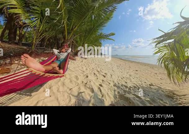 Tropical Beach Rest, Man Lying in Red Hammock Facing Ocean Under Palm ...