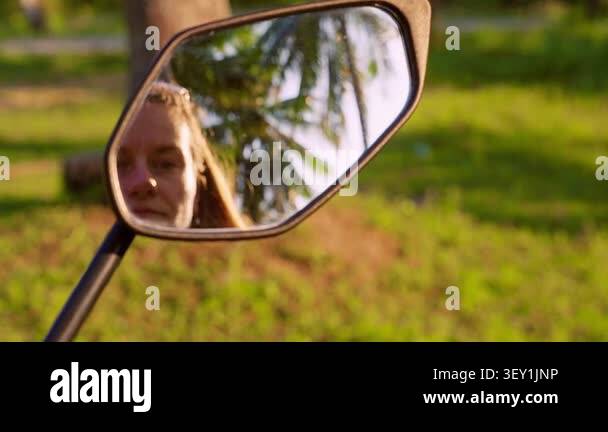 Woman Adjusting Hair Reflected in Scooter Mirror with Palm Trees and ...