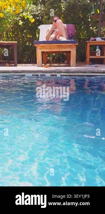 Vertical video. Low Angle View Across Clear Swimming Pool Water Toward ...