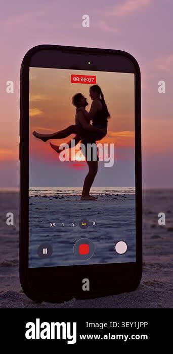 Vertical video. Smartphone Recording Woman Leaping into Man Arms and ...