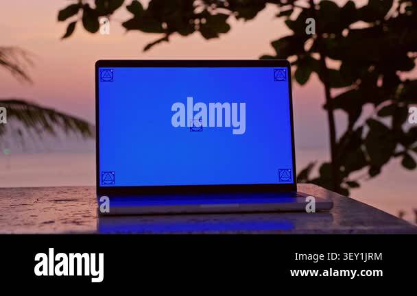 Laptop with Blue Screen Mockup on Outdoor Table at Sunset with Tropical ...
