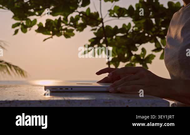Young Woman Opening Laptop at Seaside Table During Sunset with Ocean ...