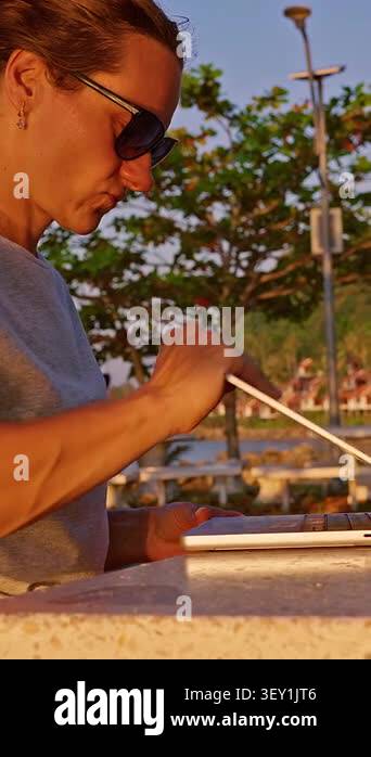 Vertical video. Young Woman Working on Laptop at Seaside During Sunset ...