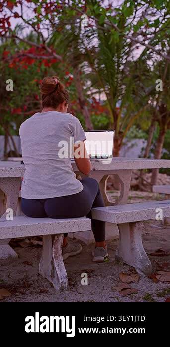 Vertical video. Woman Sitting at Outdoor Table Working on Laptop During ...