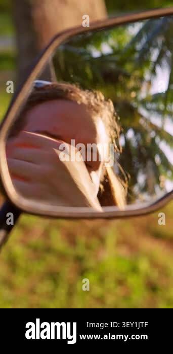 Vertical video. Woman Adjusting Hair Reflected in Scooter Mirror with ...