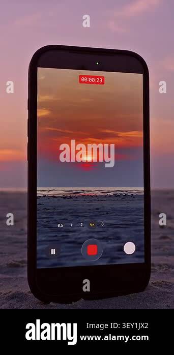Vertical video. Smartphone Recording Sunset Over Ocean on Beach with ...