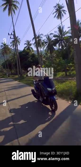 Vertical video. Side View of Young Woman Riding Scooter on Tropical ...