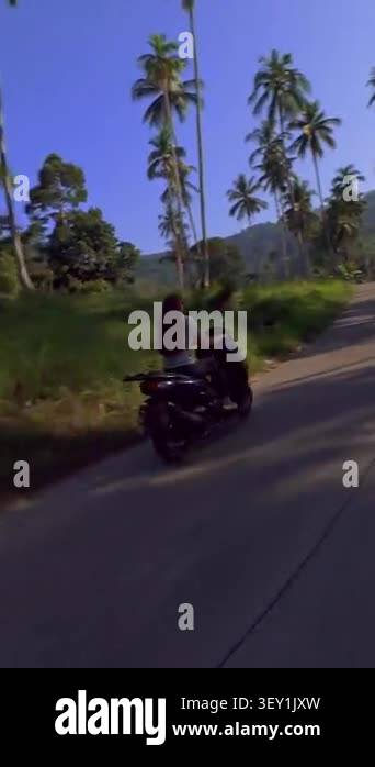 Vertical video. Rear View of Young Woman Riding Scooter Along Empty ...