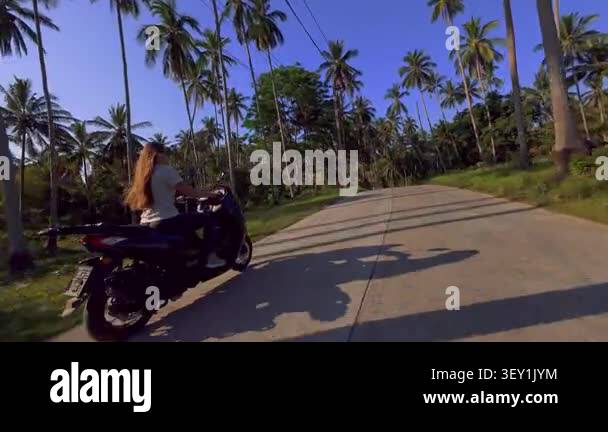 Side View of Young Woman Riding Scooter Along Tropical Road With Palm ...